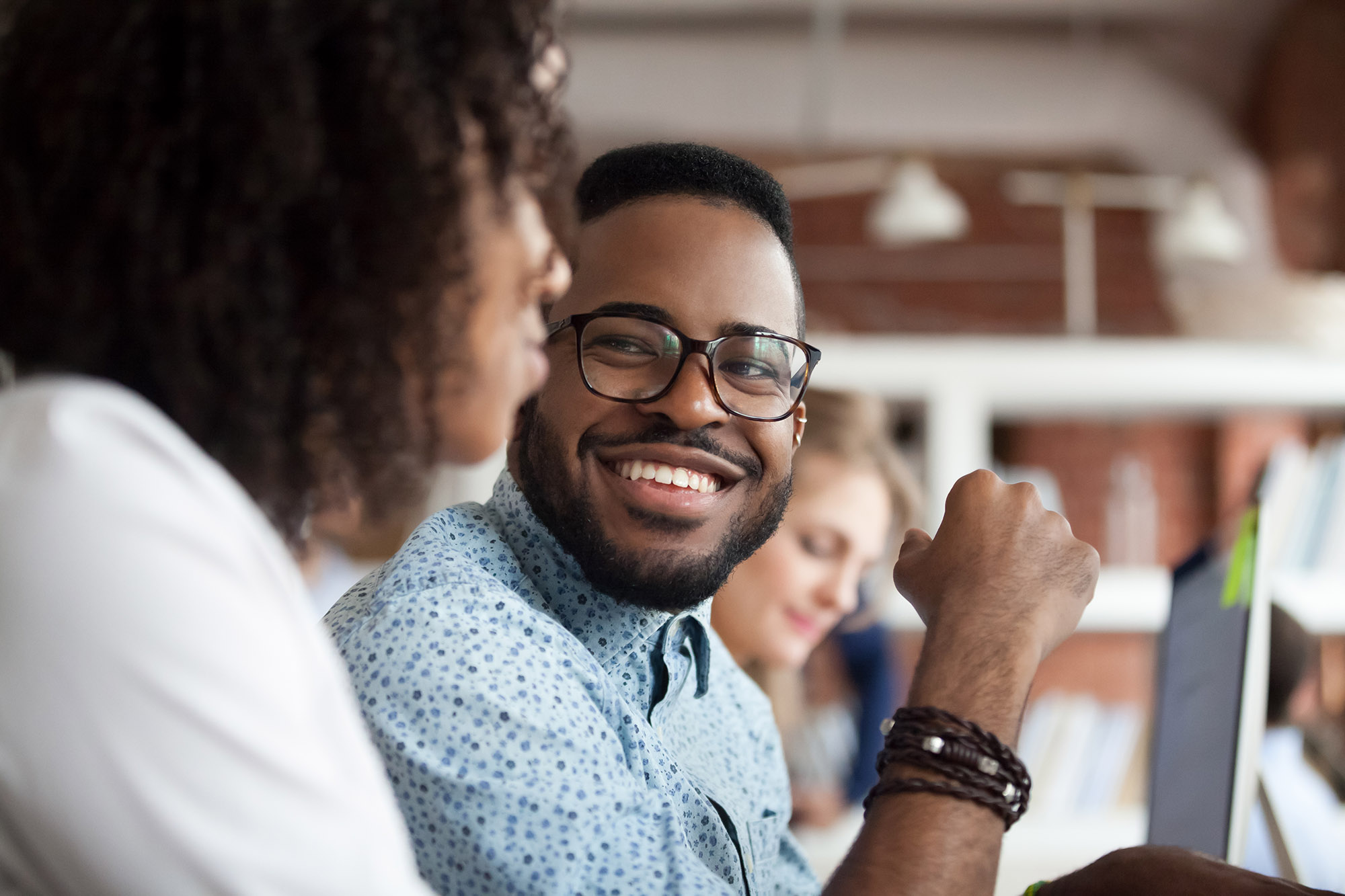 Smiling African American male employee look at colleague chattin | PQS Smiling African American male employee look at colleague chattin | PQS